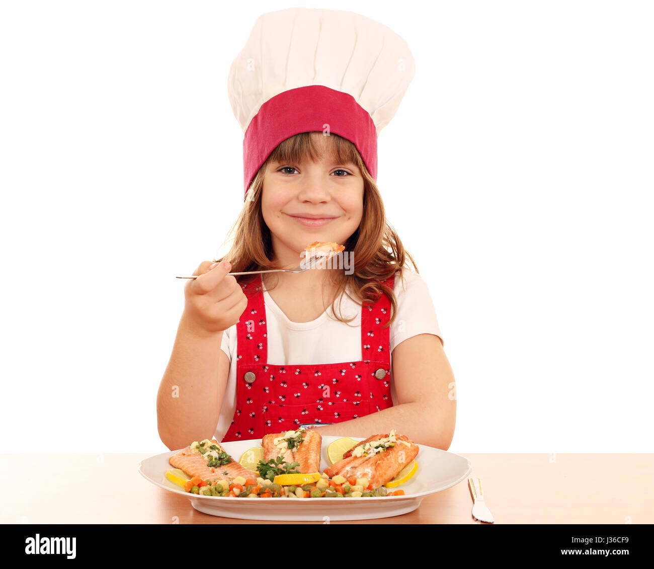 hungry little girl cook eating salmon Stock Photo - Alamy