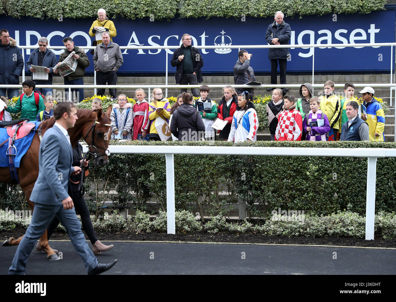 School children on a tour watch horses pass in the parade ring during ...