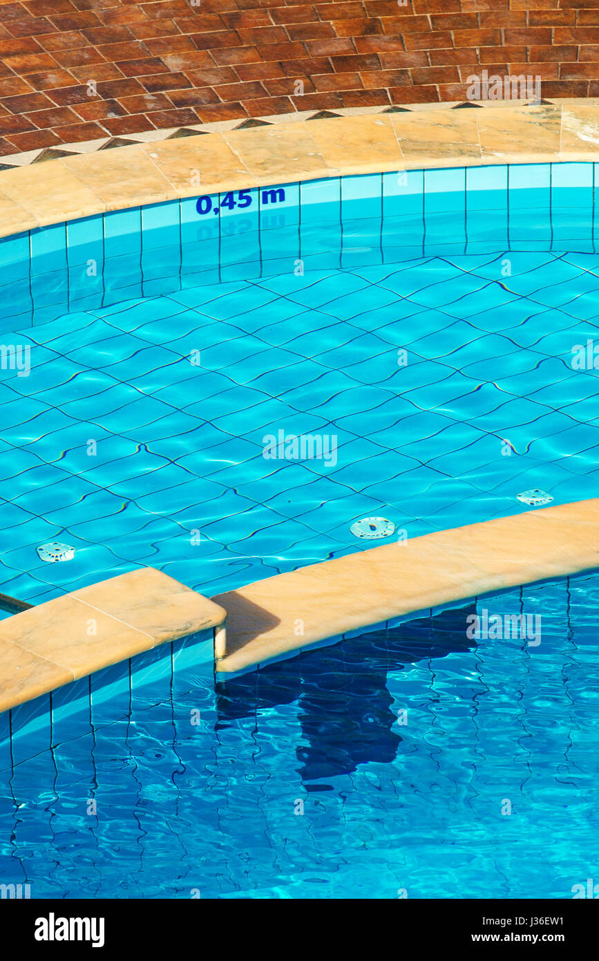 Outdoor poolside on summer afternoon, clear transparent swimming pool ...