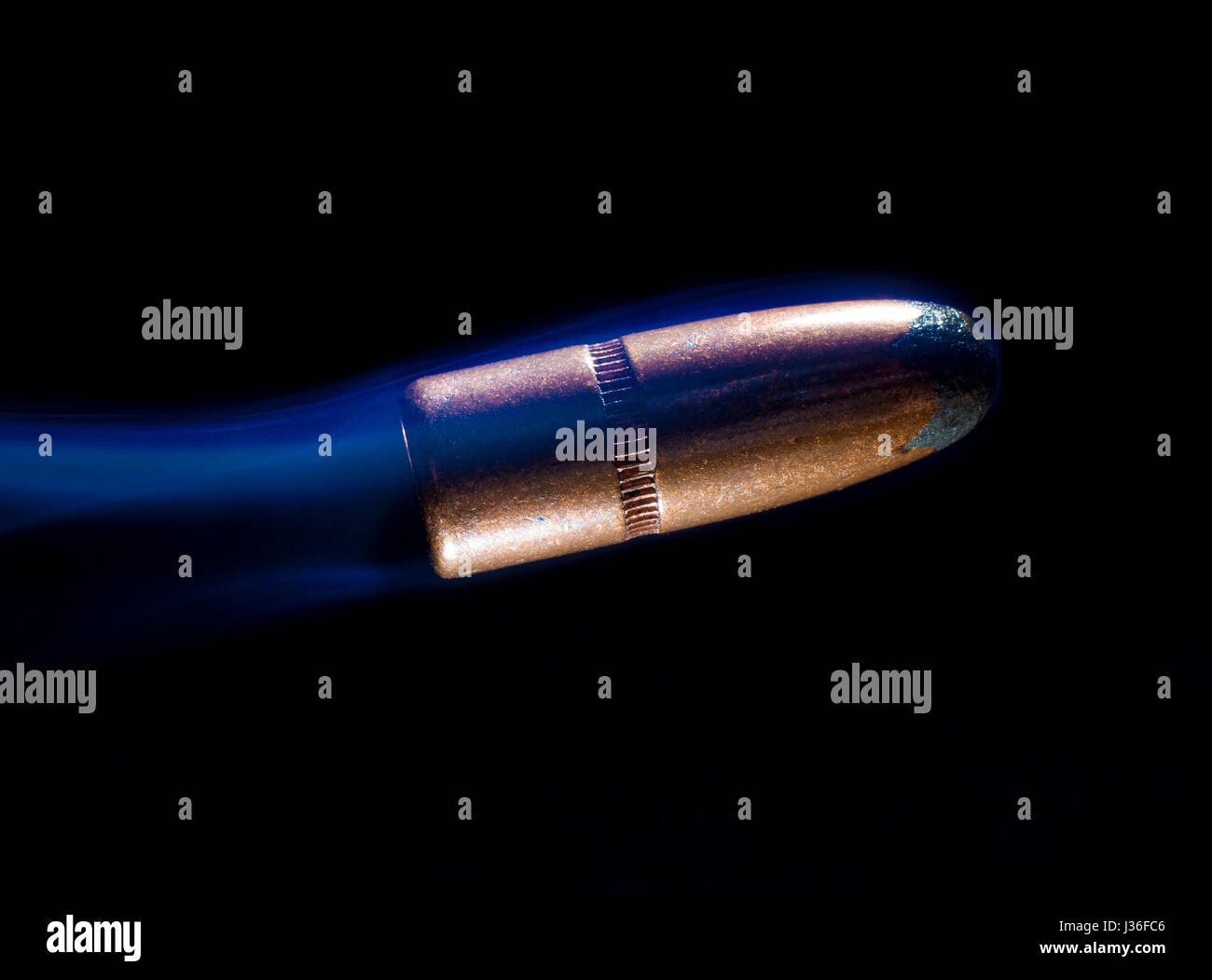Blue smoke trailing a copper plated bullet on a black background Stock ...