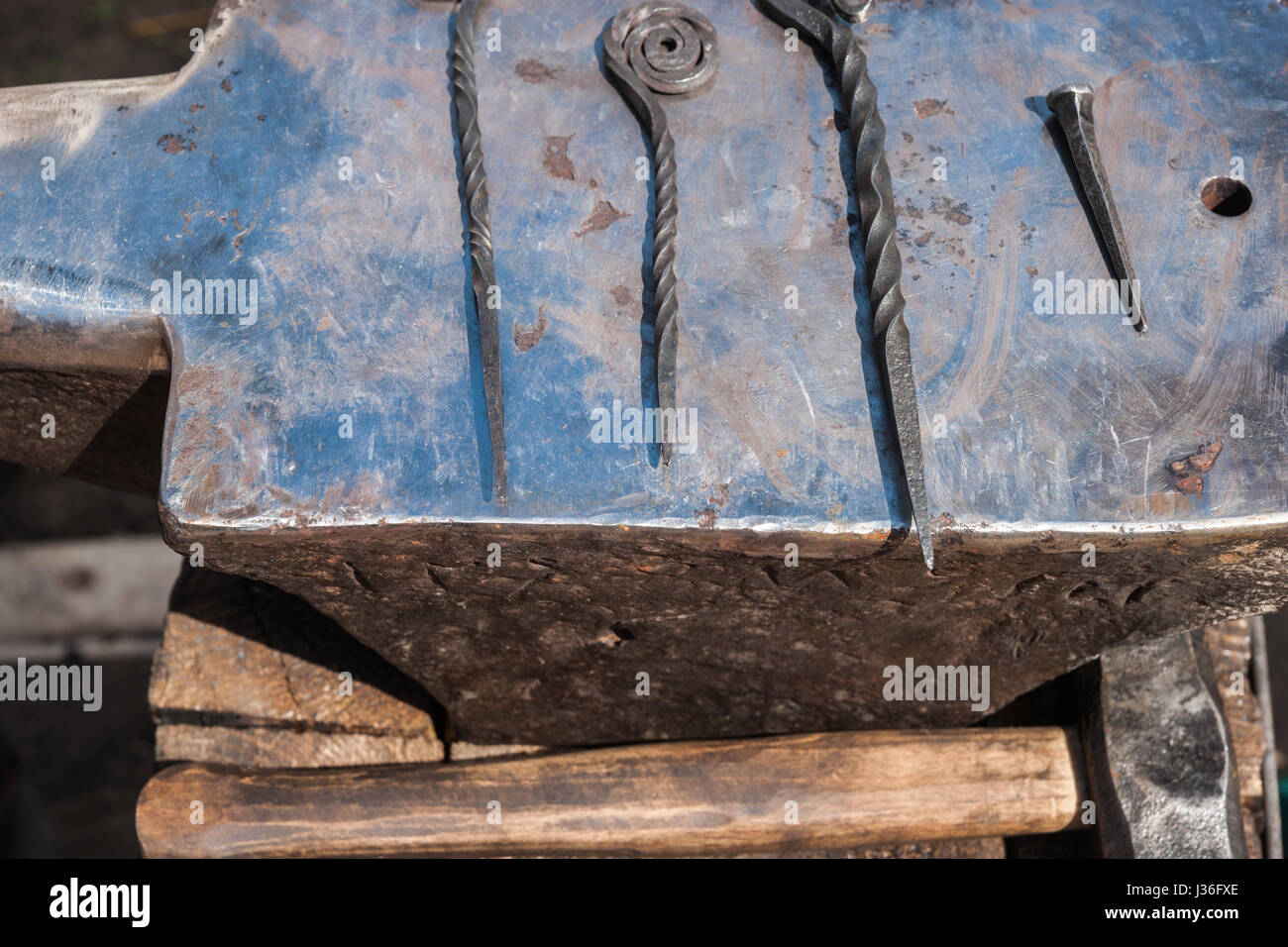 Forged medieval metalware on an anvil. The hammer lays by the anvil ...