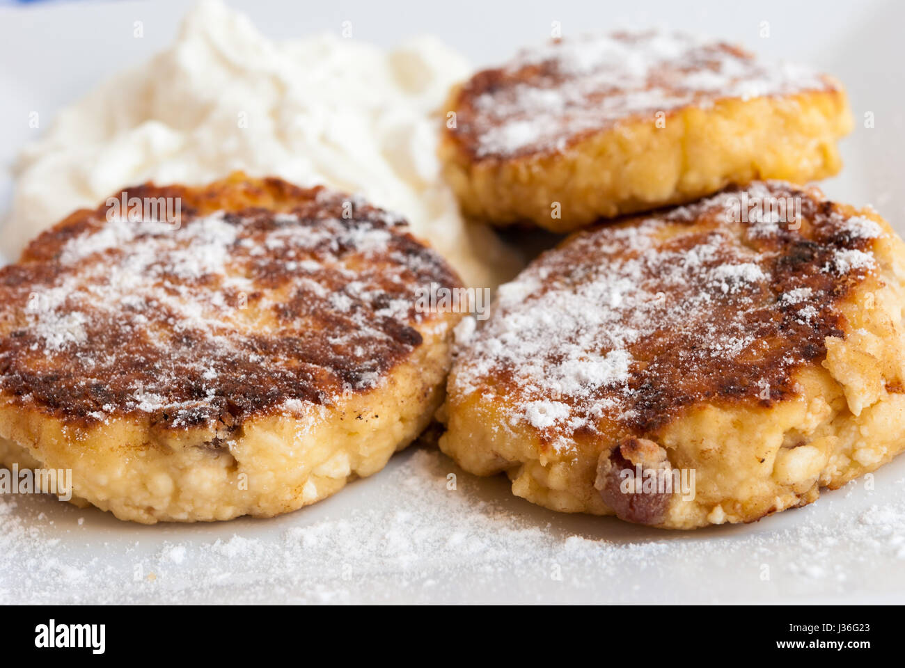 Syrniki (Russian and Ukrainian pancakes) served with sour cream closeup ...