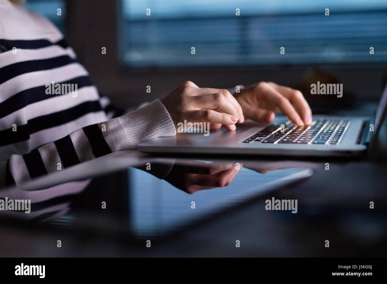 Unrecognizable woman sitting at desk working on laptop Stock Photo - Alamy