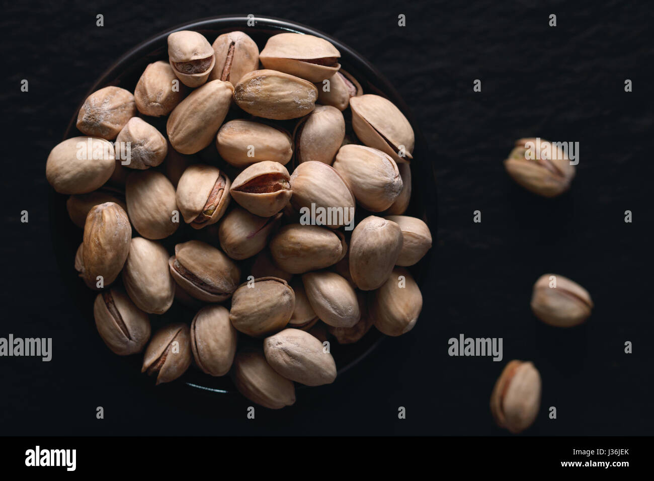 Roasted pistachios on the dark background. Dark food photography. Top ...