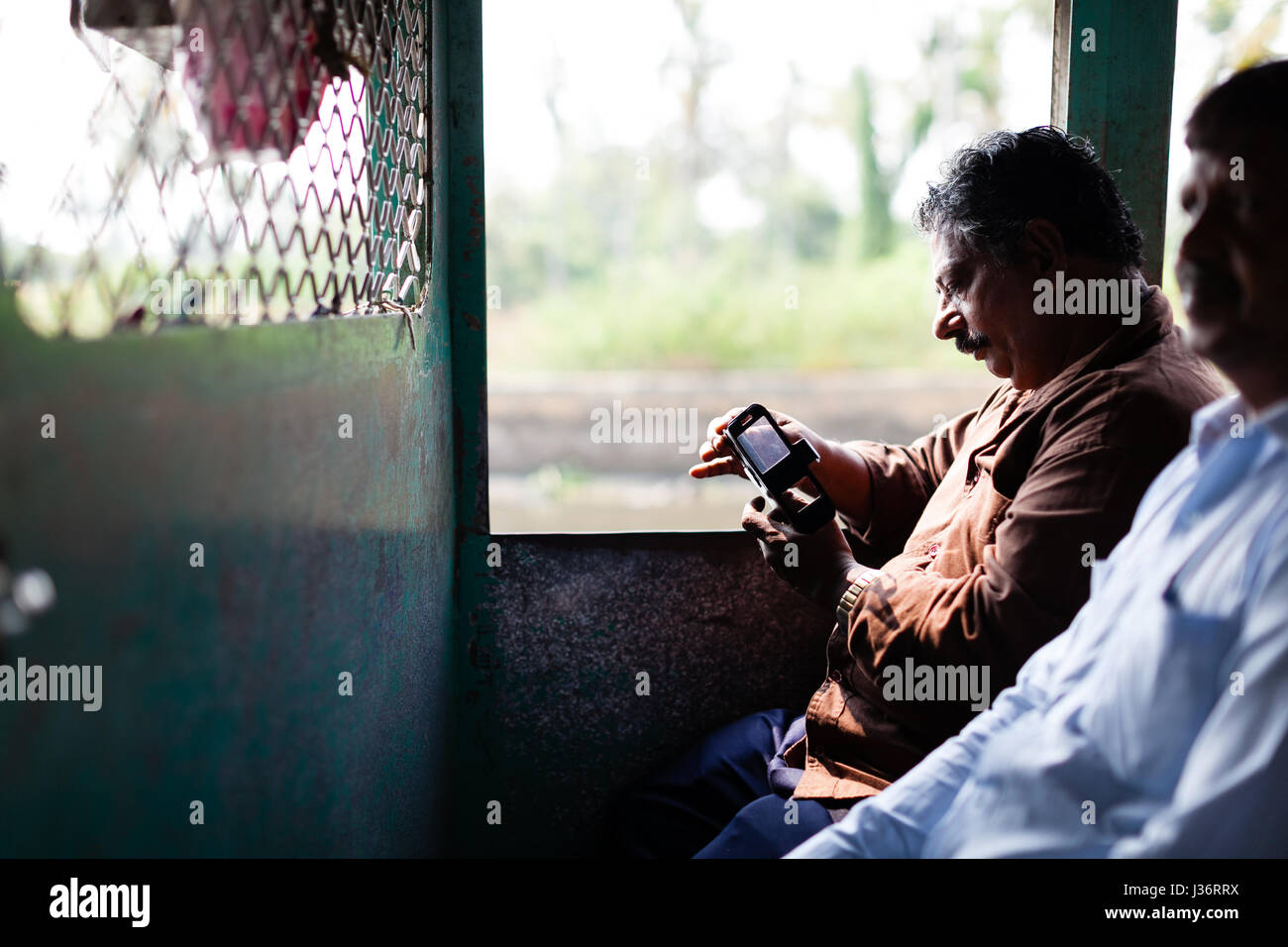 Indian technology - a man checks his phone while travelling by public ...