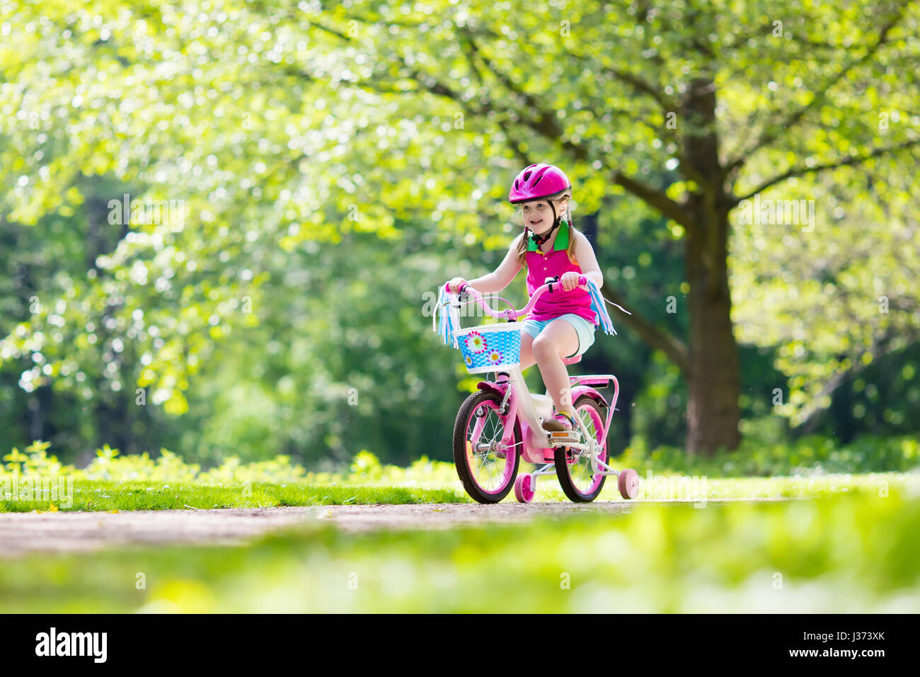 Child riding bike. Kid on bicycle in sunny park. Little girl enjoying ...