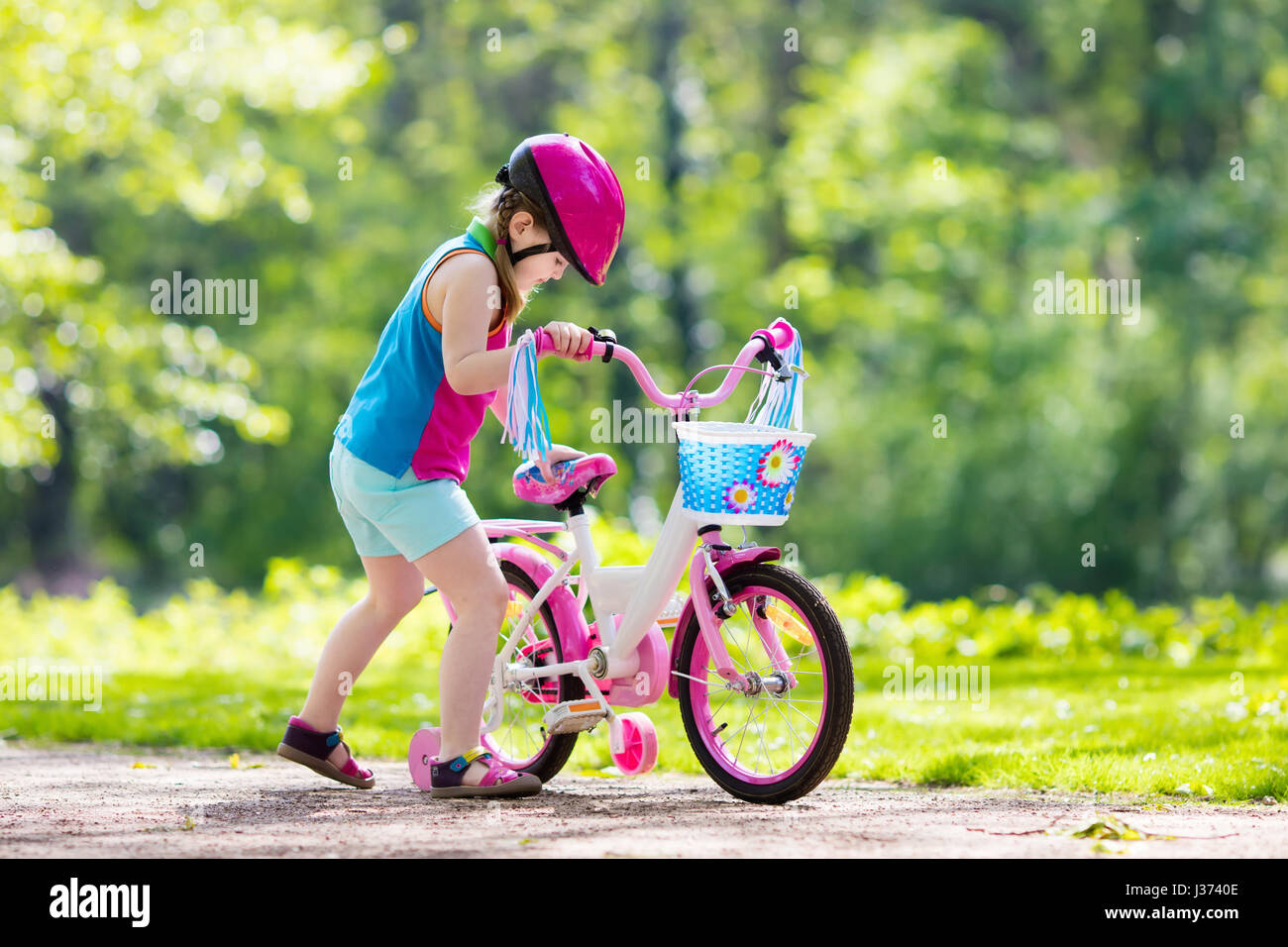 Child riding bike. Kid on bicycle in sunny park. Little girl enjoying ...