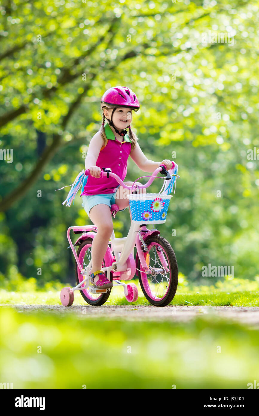 Child riding bike. Kid on bicycle in sunny park. Little girl enjoying ...