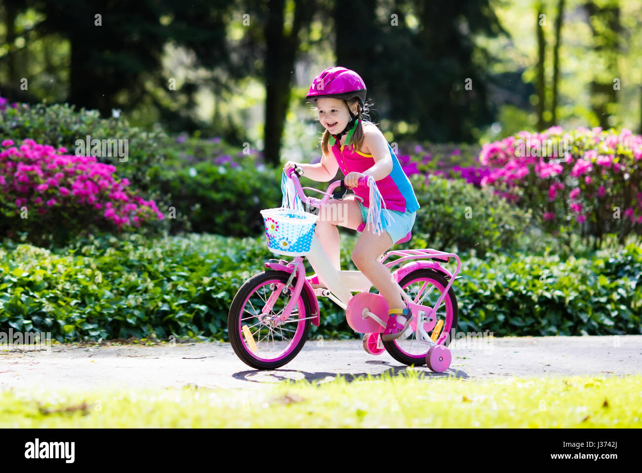 Child riding bike. Kid on bicycle in sunny park. Little girl enjoying ...