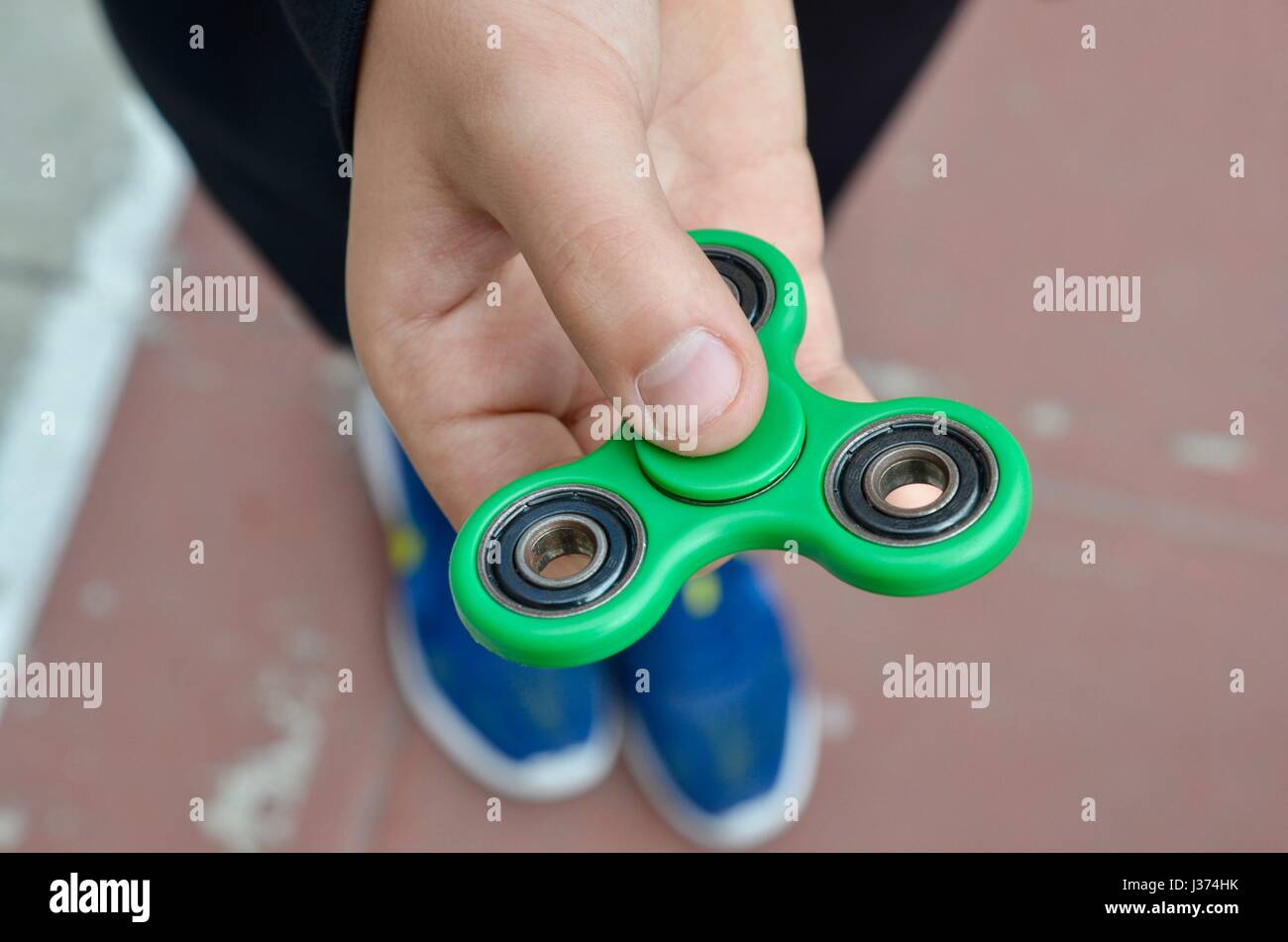 A boy playing with a green fidget spinner in brooklyn new york USA ...