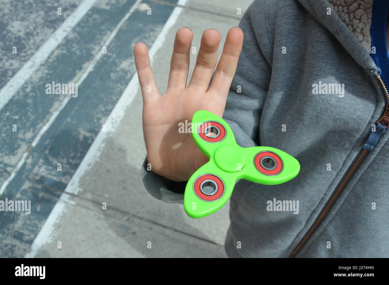 A boy playing with a green fidget spinner in brooklyn new york USA ...