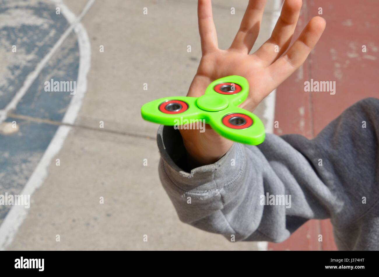 A boy playing with a green fidget spinner in brooklyn new york USA ...