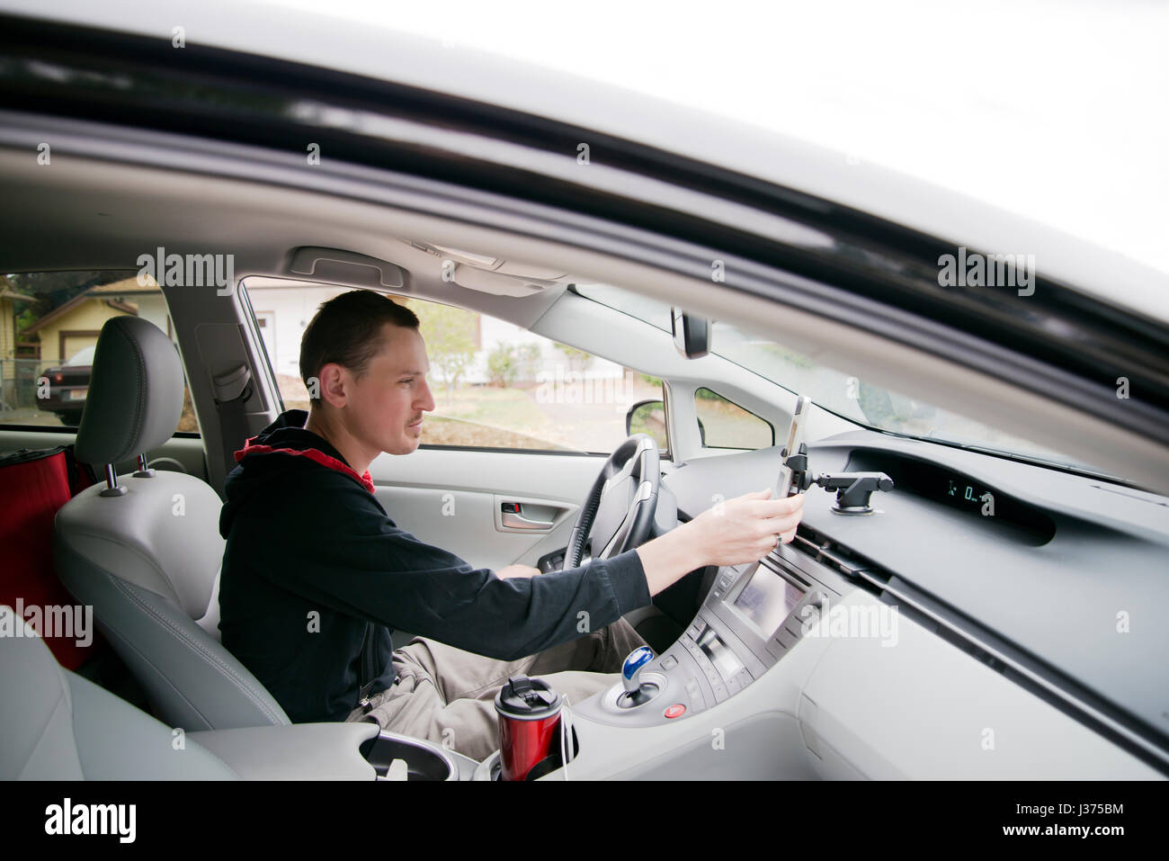 Young driver with a smile and good mood adjusts hand touch screen ...