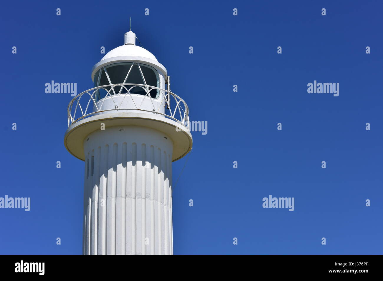 Top part of white lighthouse showing circular railing and glass panes ...