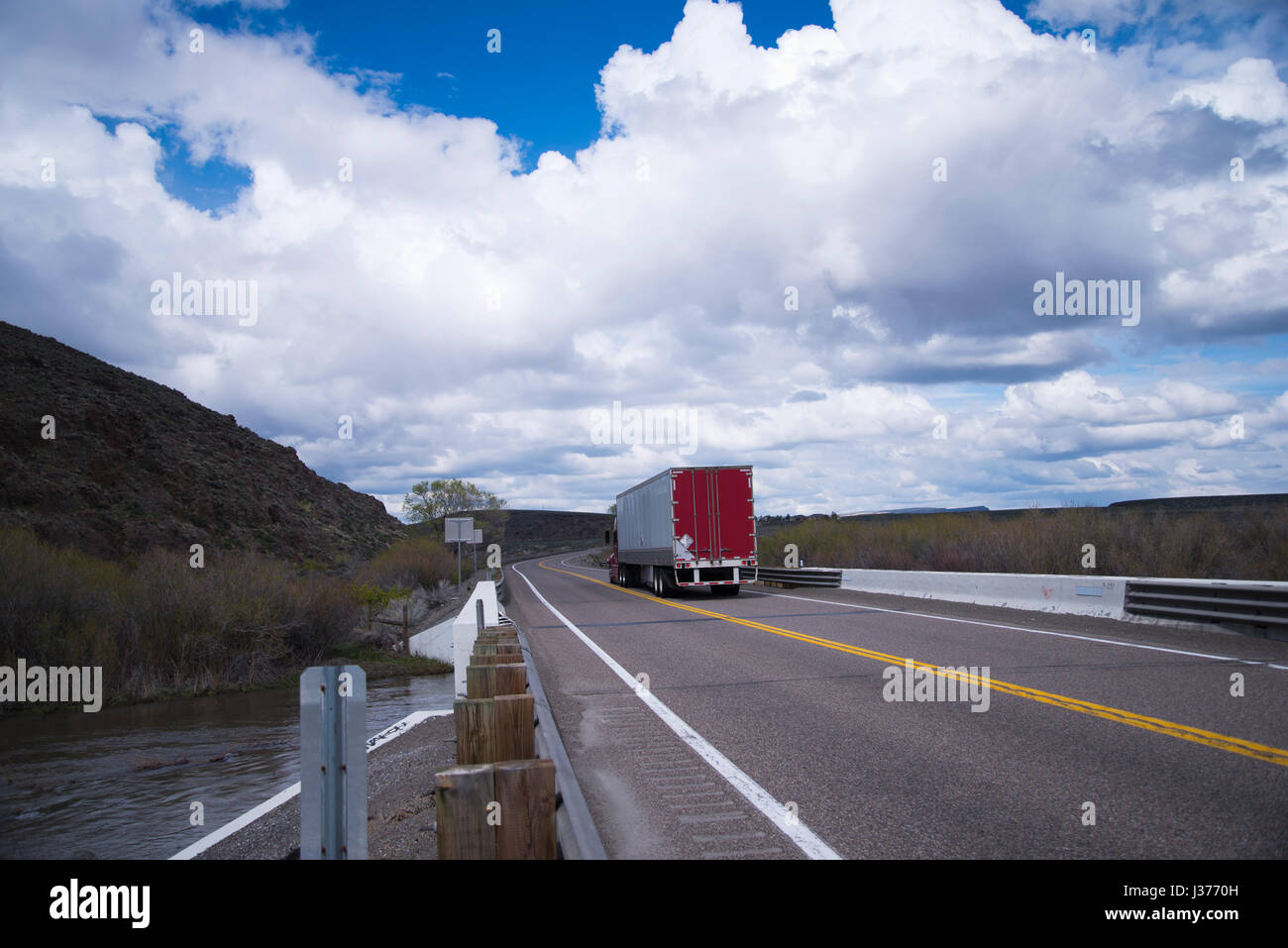Moving semi truck with the load in a dry van trailer with red doors on ...