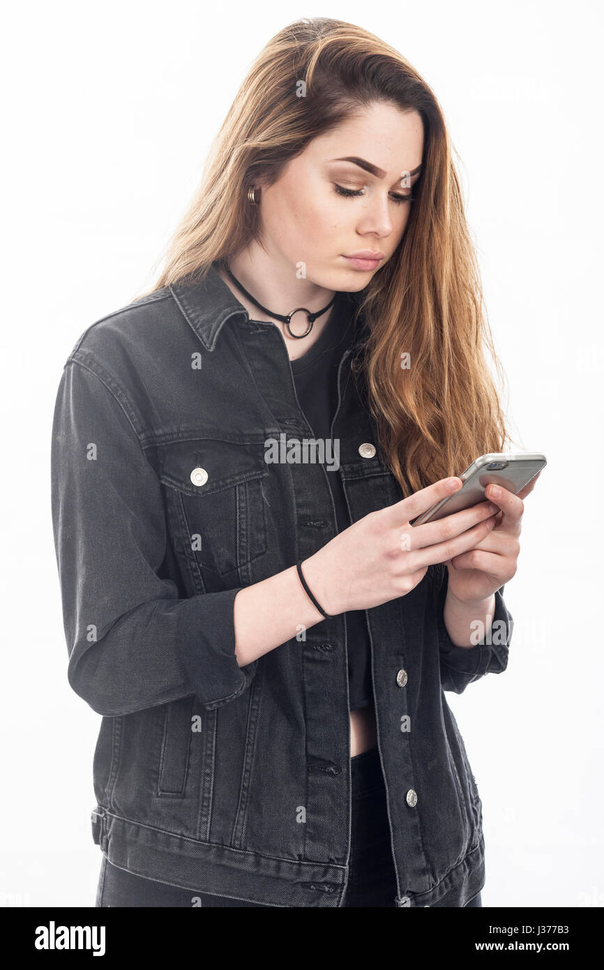 A pretty 15 year old girl texting / messaging on smartphone in the ...