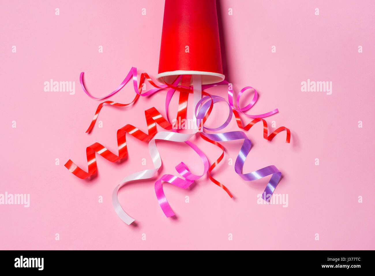 Flat lay of Celebration. Paper cup with colorful party streamers on ...