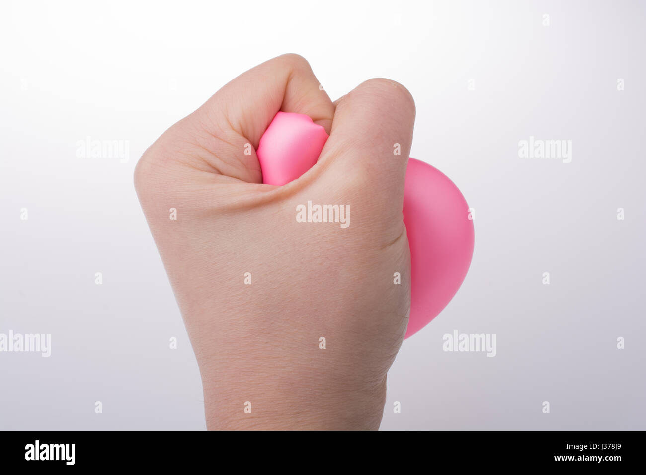 Squeezing pink balloon with hand on a white background Stock Photo - Alamy