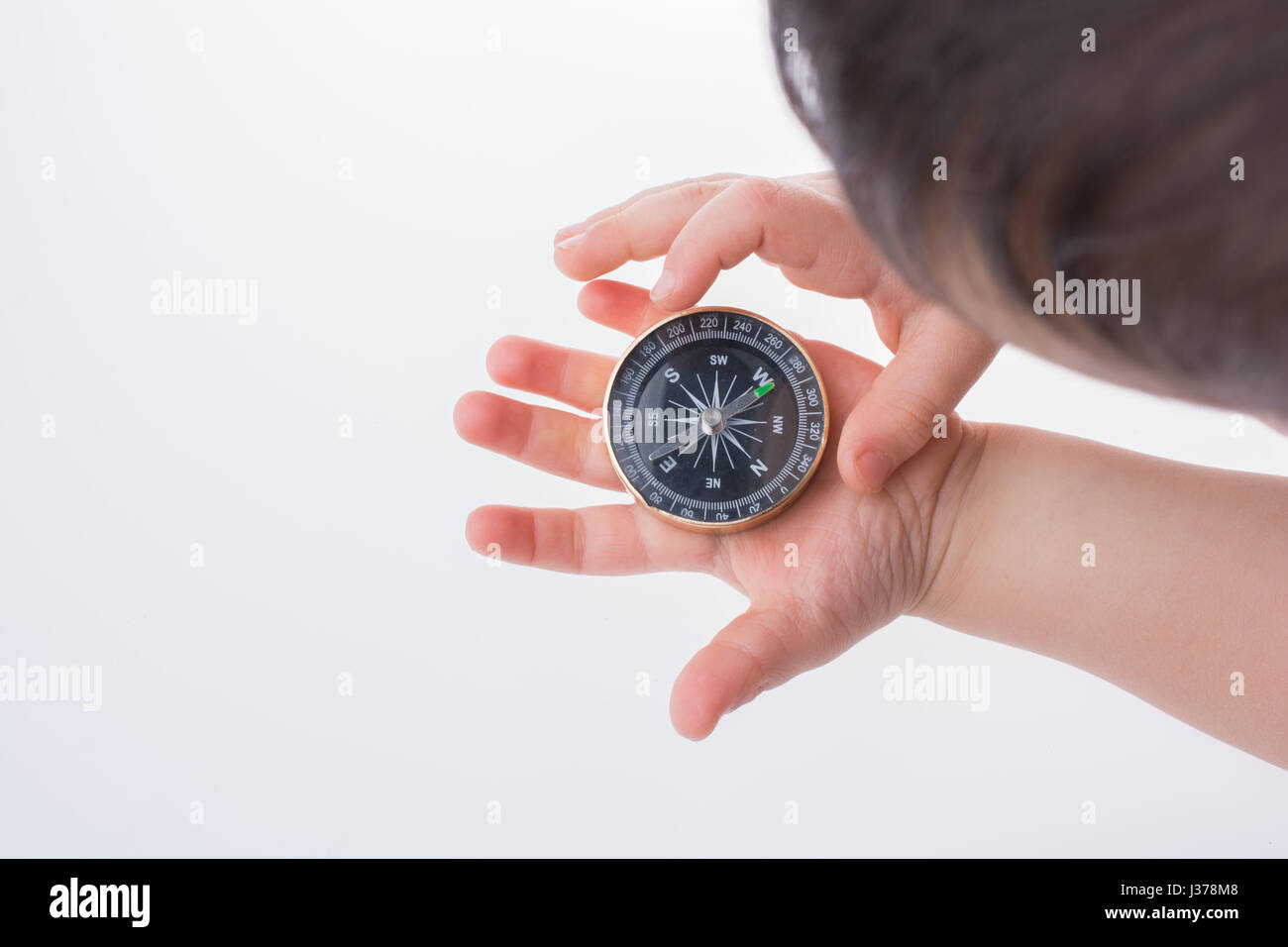 Child hand holding a compass on a white background Stock Photo - Alamy