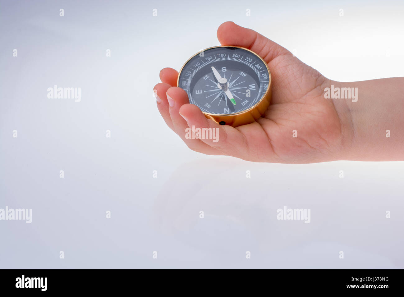 Child hand holding a compass on a white background Stock Photo - Alamy