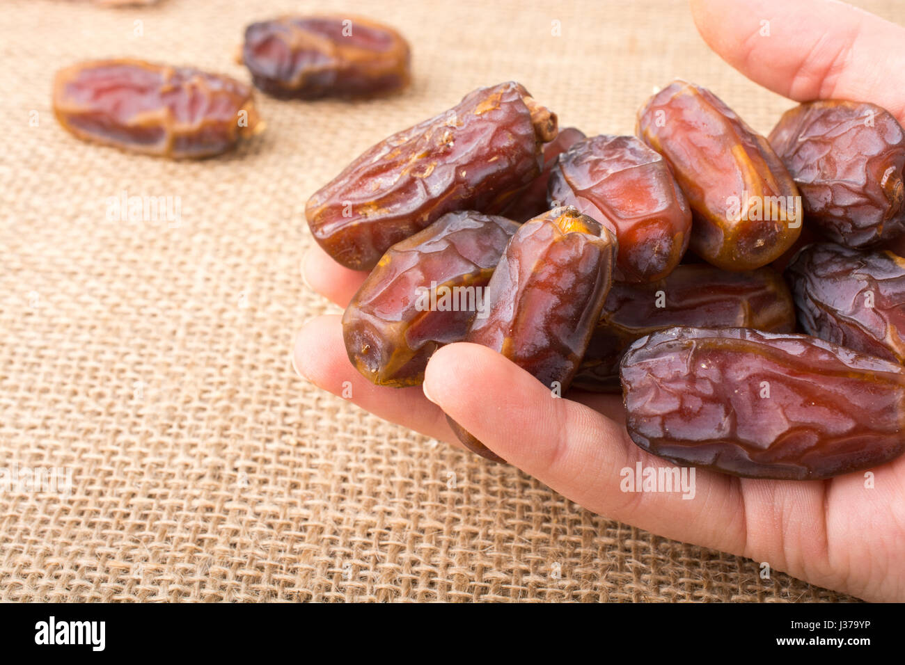 hand holding dates on a linen canvas background Stock Photo - Alamy
