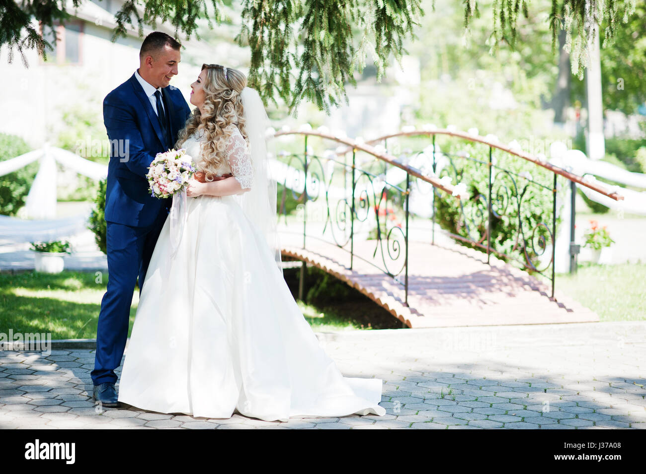 Happy wedding couple in love near small bridge at park on sunny day ...