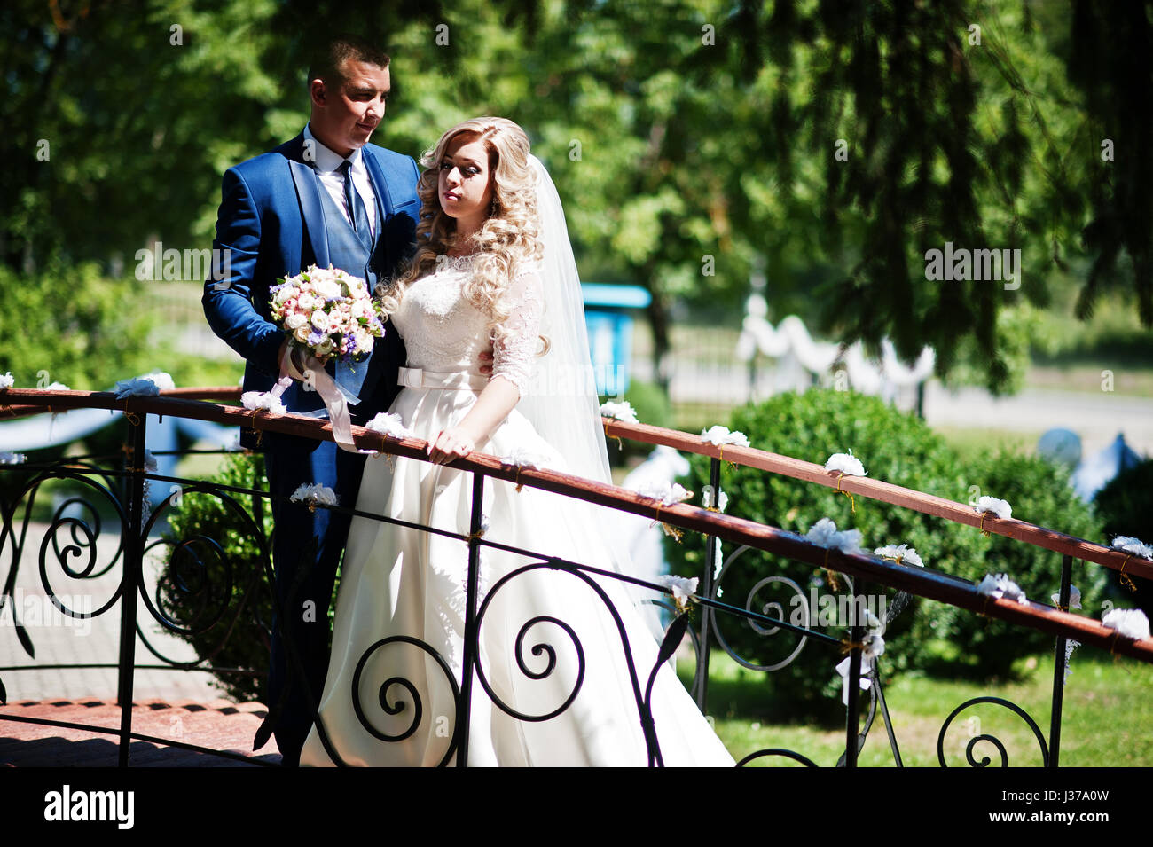 Happy wedding couple in love near small bridge at park on sunny day ...