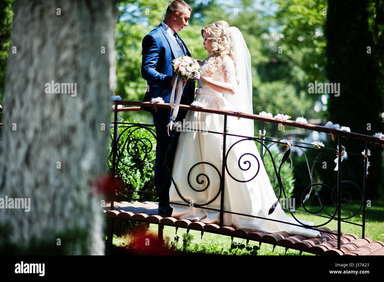 Happy wedding couple in love near small bridge at park on sunny day ...