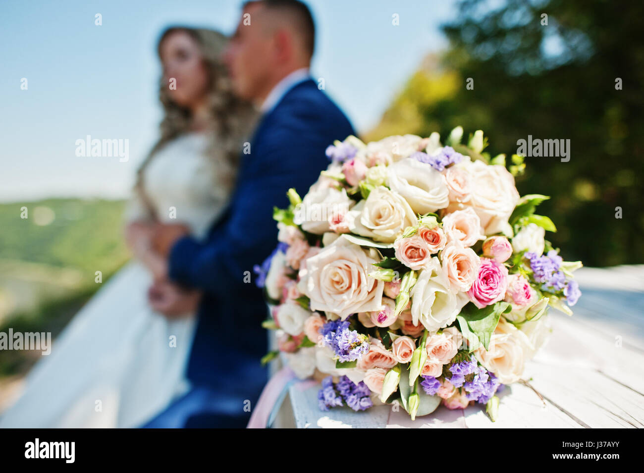 Wedding bouquet on wooden table against wedding couple Stock Photo - Alamy