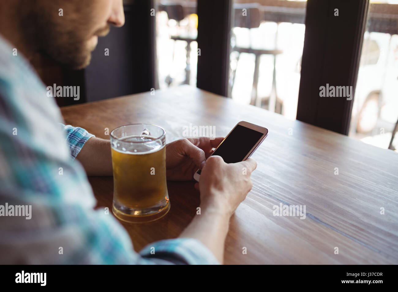 Man using mobile phone while having beer in bar Stock Photo - Alamy