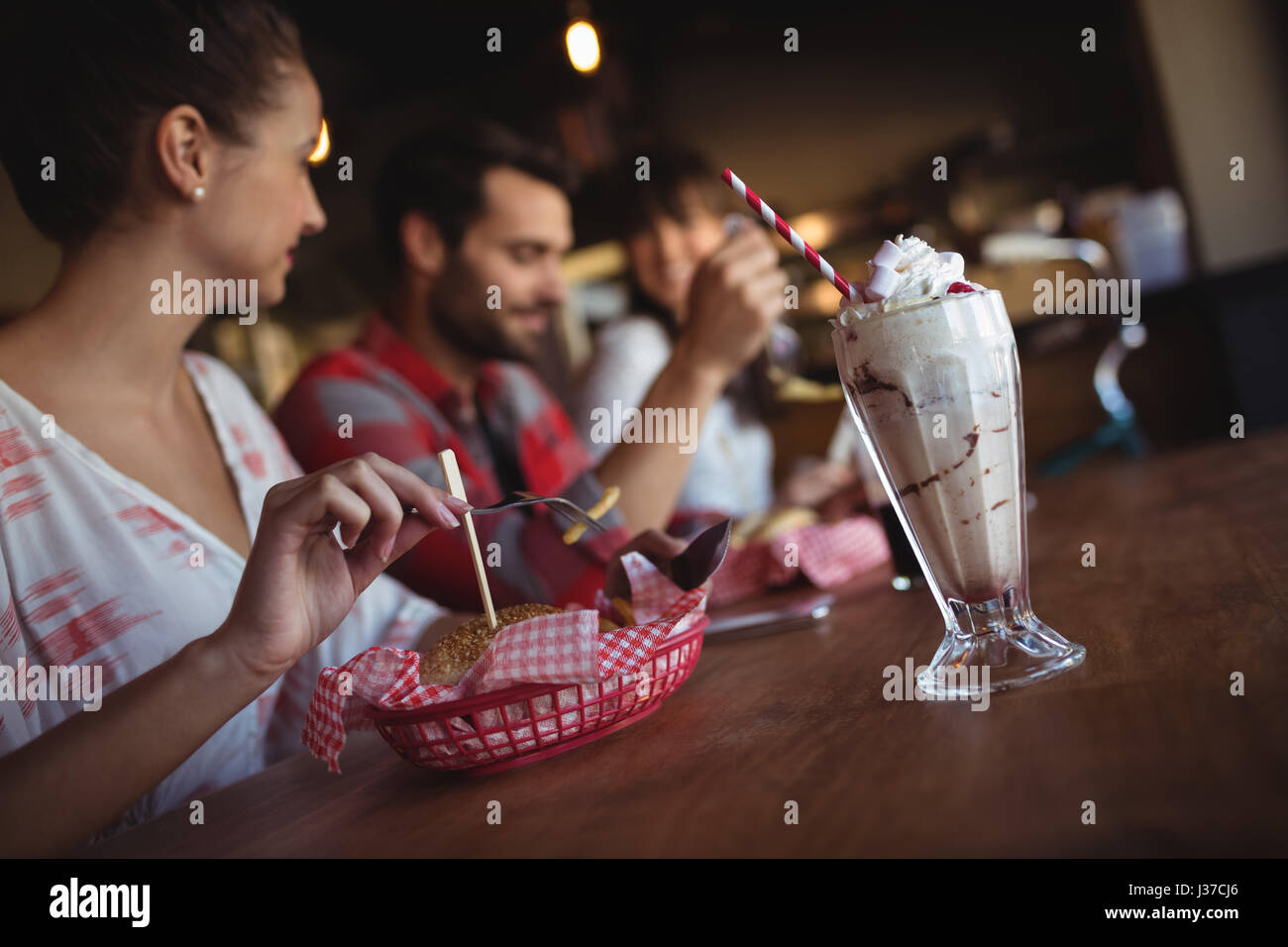 Friends having burger together at restaurant Stock Photo - Alamy