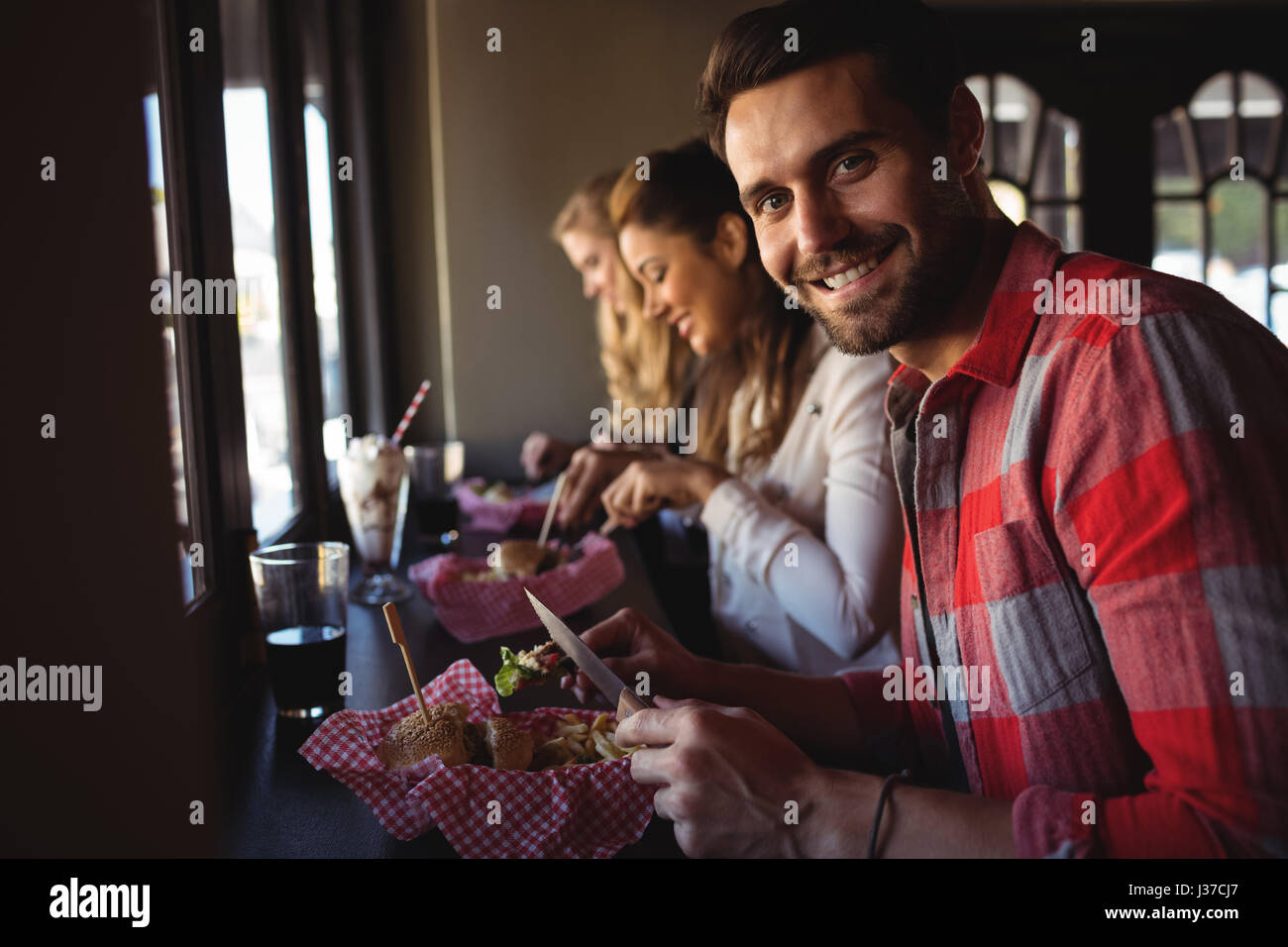 Friends having burger together at restaurant Stock Photo - Alamy