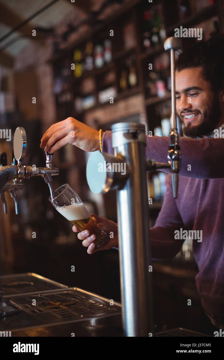 Bar tender filling beer from bar pump at bar counter Stock Photo - Alamy
