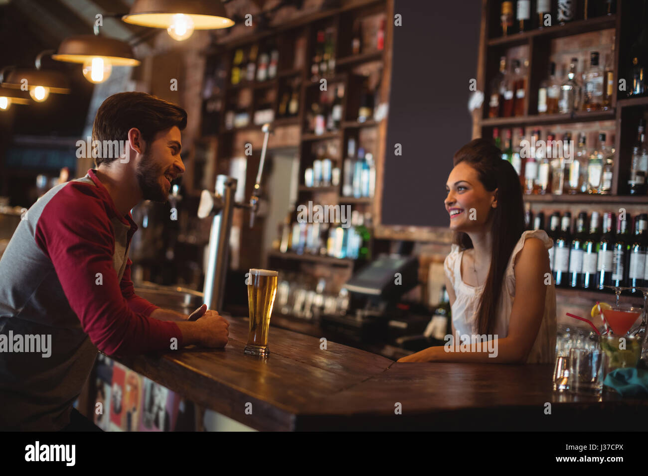 Female bar tender interacting with customer at bar counter Stock Photo ...