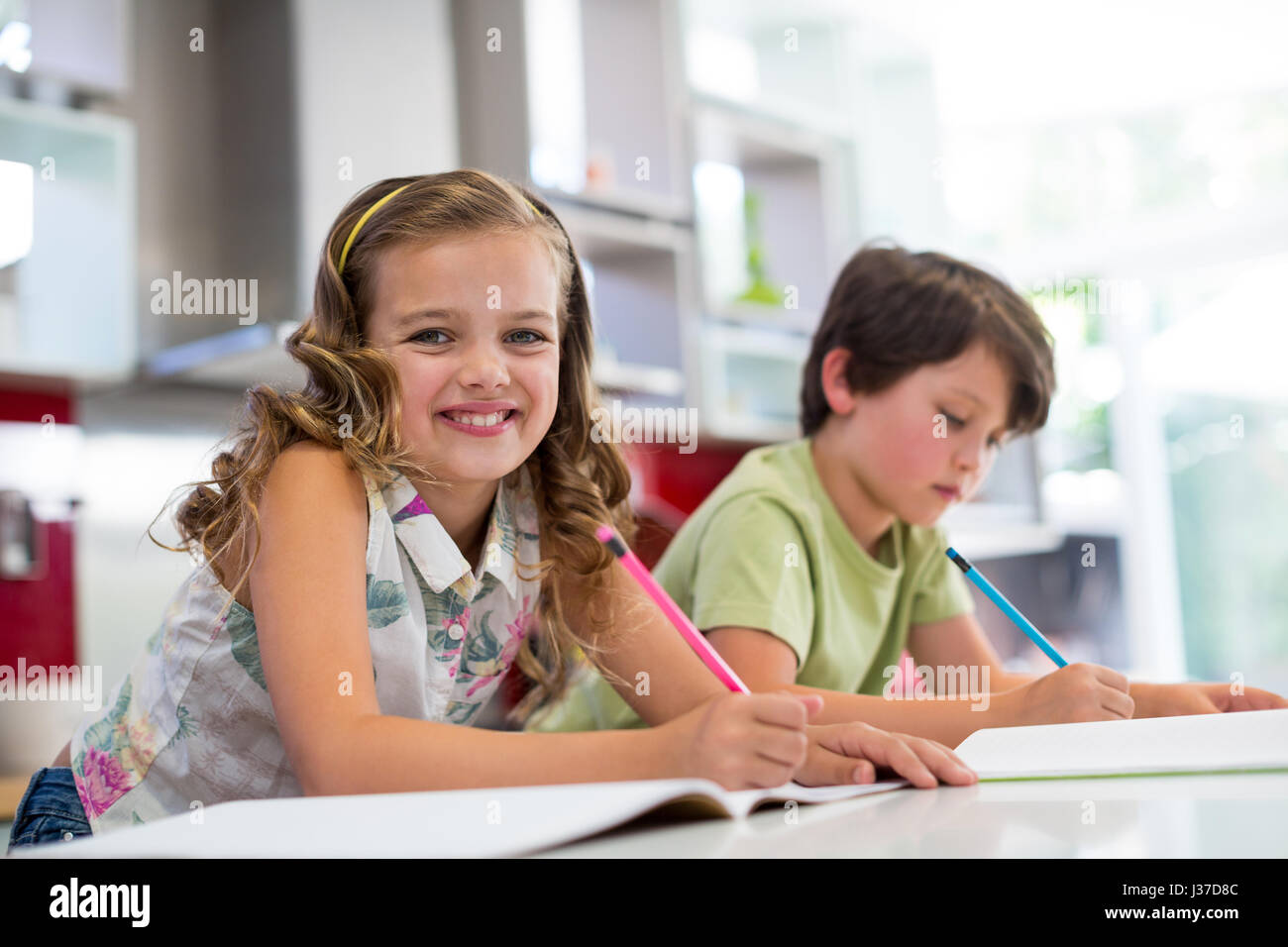 Siblings doing homework in kitchen at home Stock Photo - Alamy