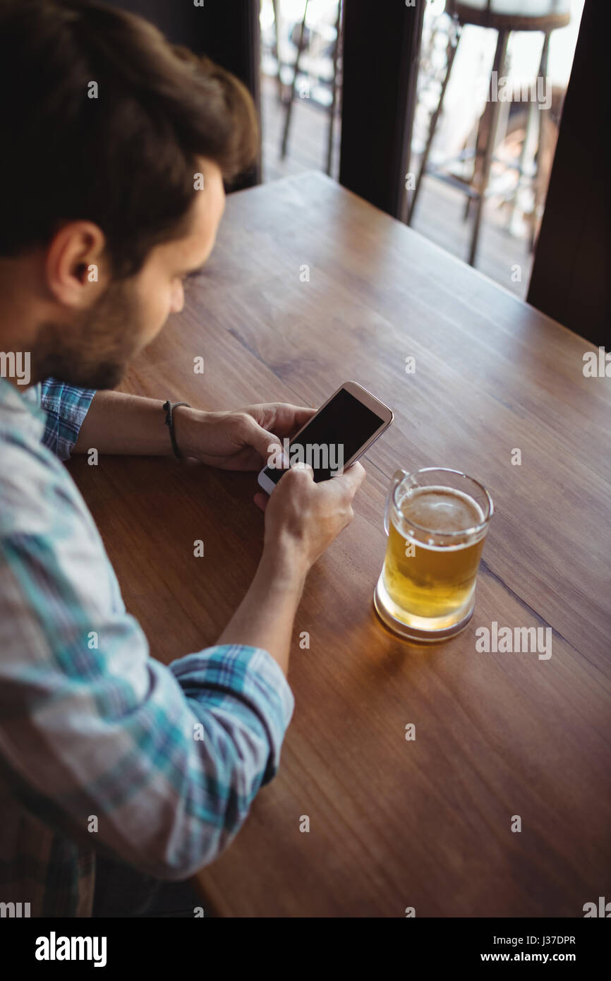 Man using mobile phone while having beer in bar Stock Photo - Alamy