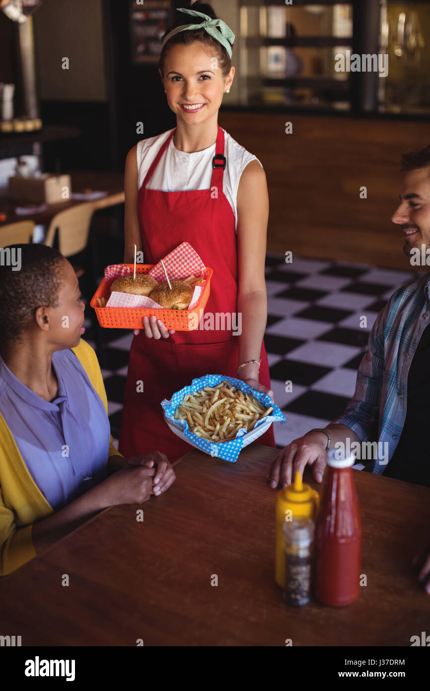 Waitress serving burger and french fries to customer at restaurant ...