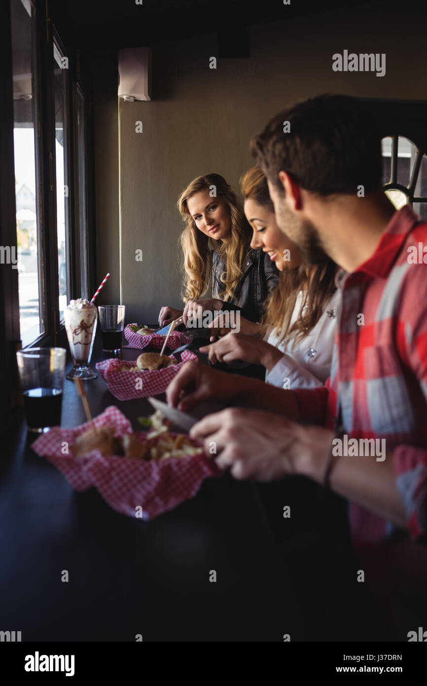 Friends having burger together at restaurant Stock Photo - Alamy