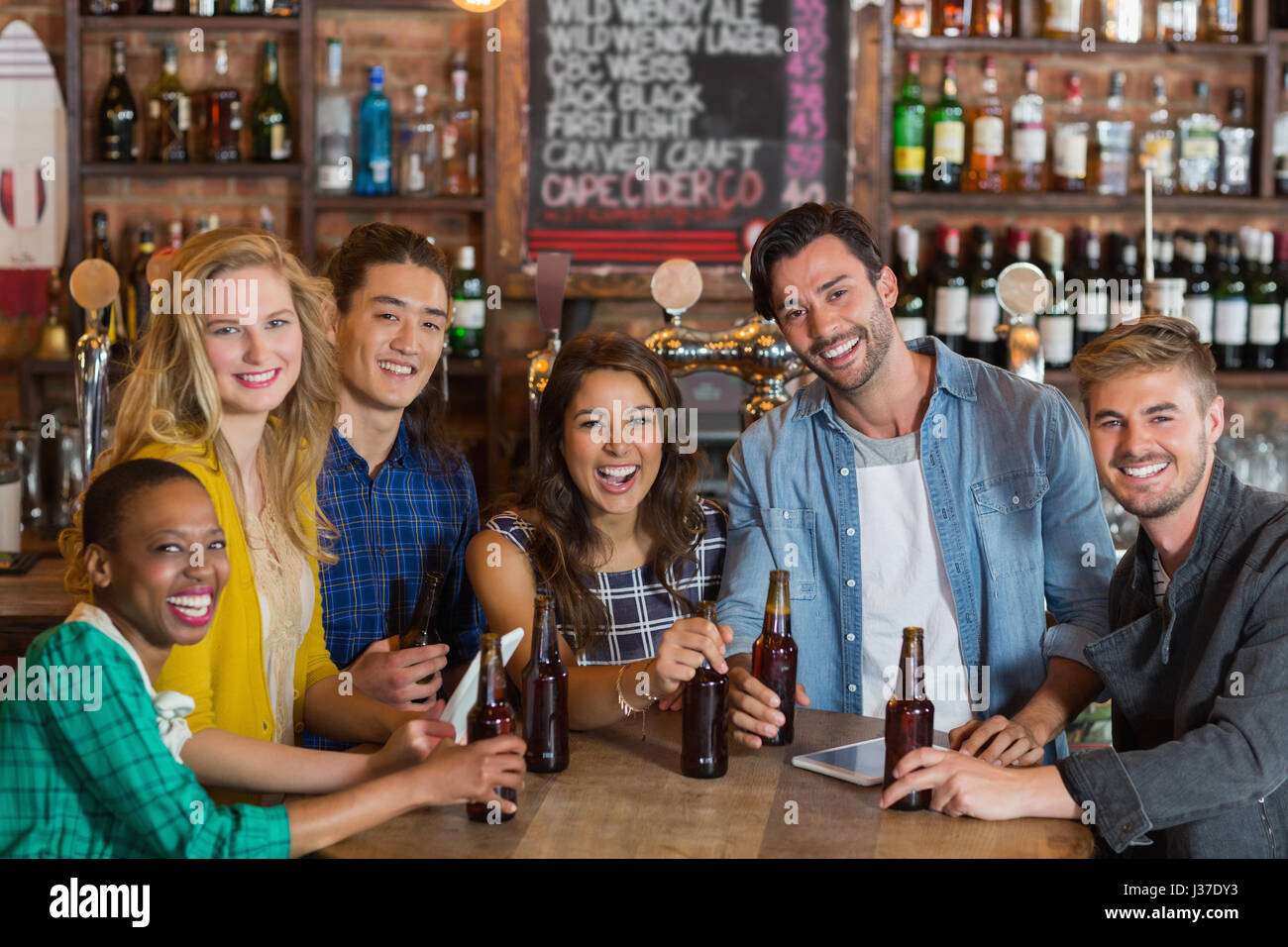 Portrait of cheerful young friends with beer bottles standing around ...