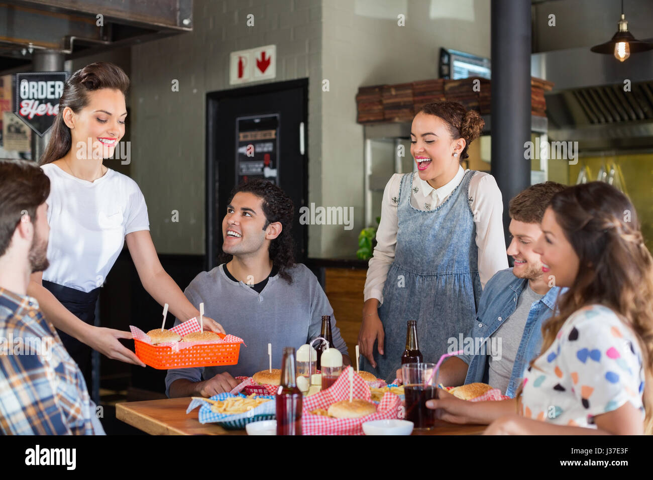 Group of friends looking at waitress serving food in restaurant Stock ...