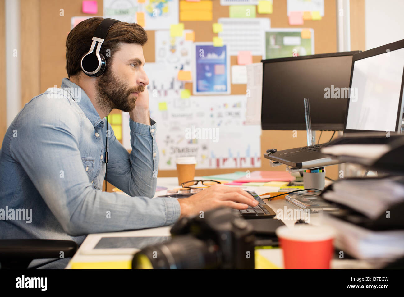 Side view of businessman wearing headphones while working in creative ...