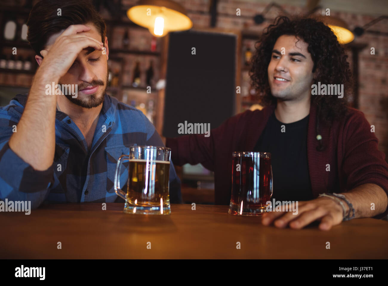 Man comforting his depressed friend in pub Stock Photo - Alamy