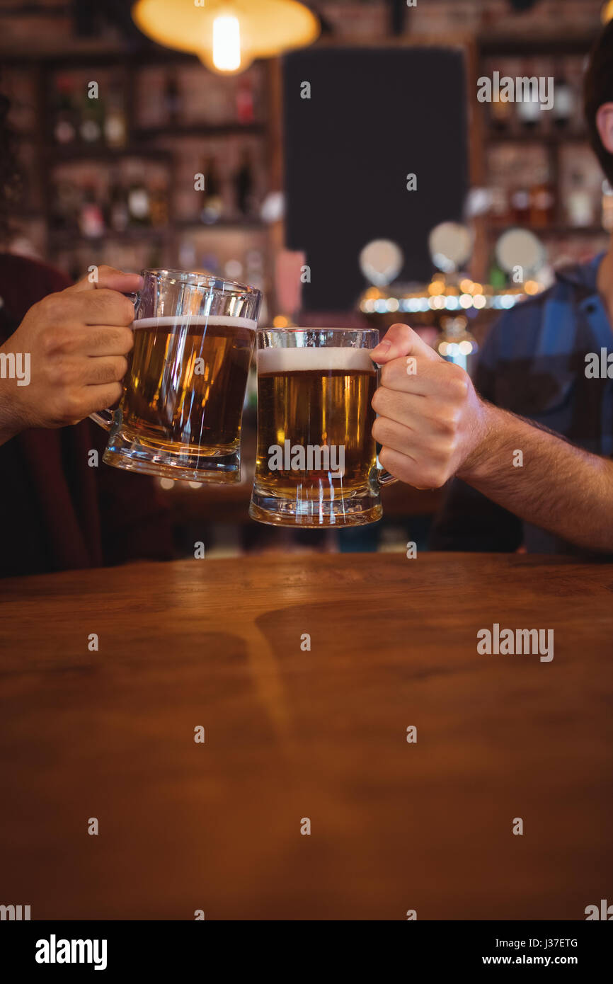 Two young men toasting their beer mugs in pub Stock Photo - Alamy