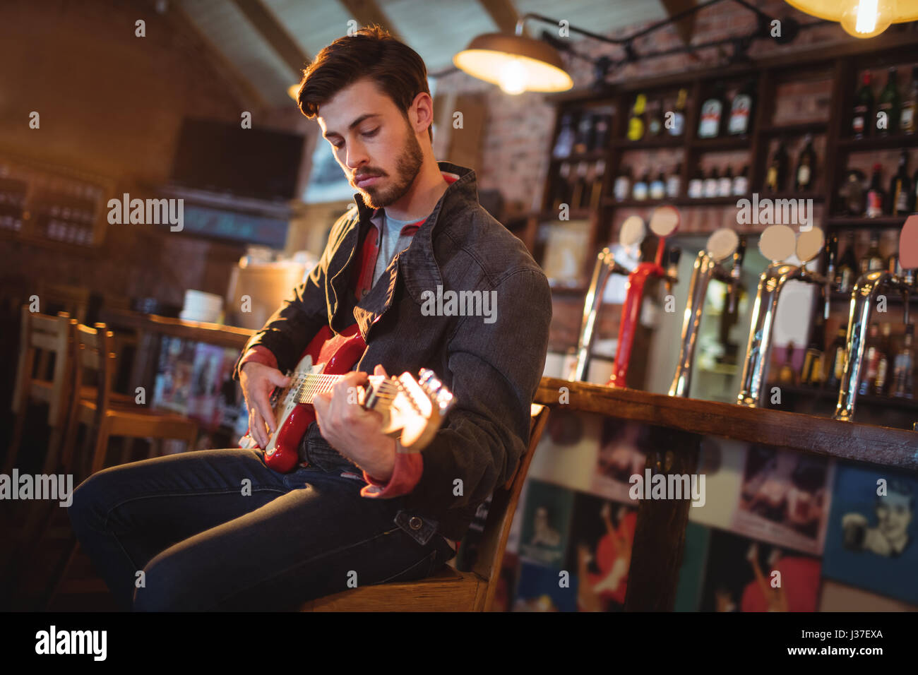Young man playing guitar in pub Stock Photo - Alamy
