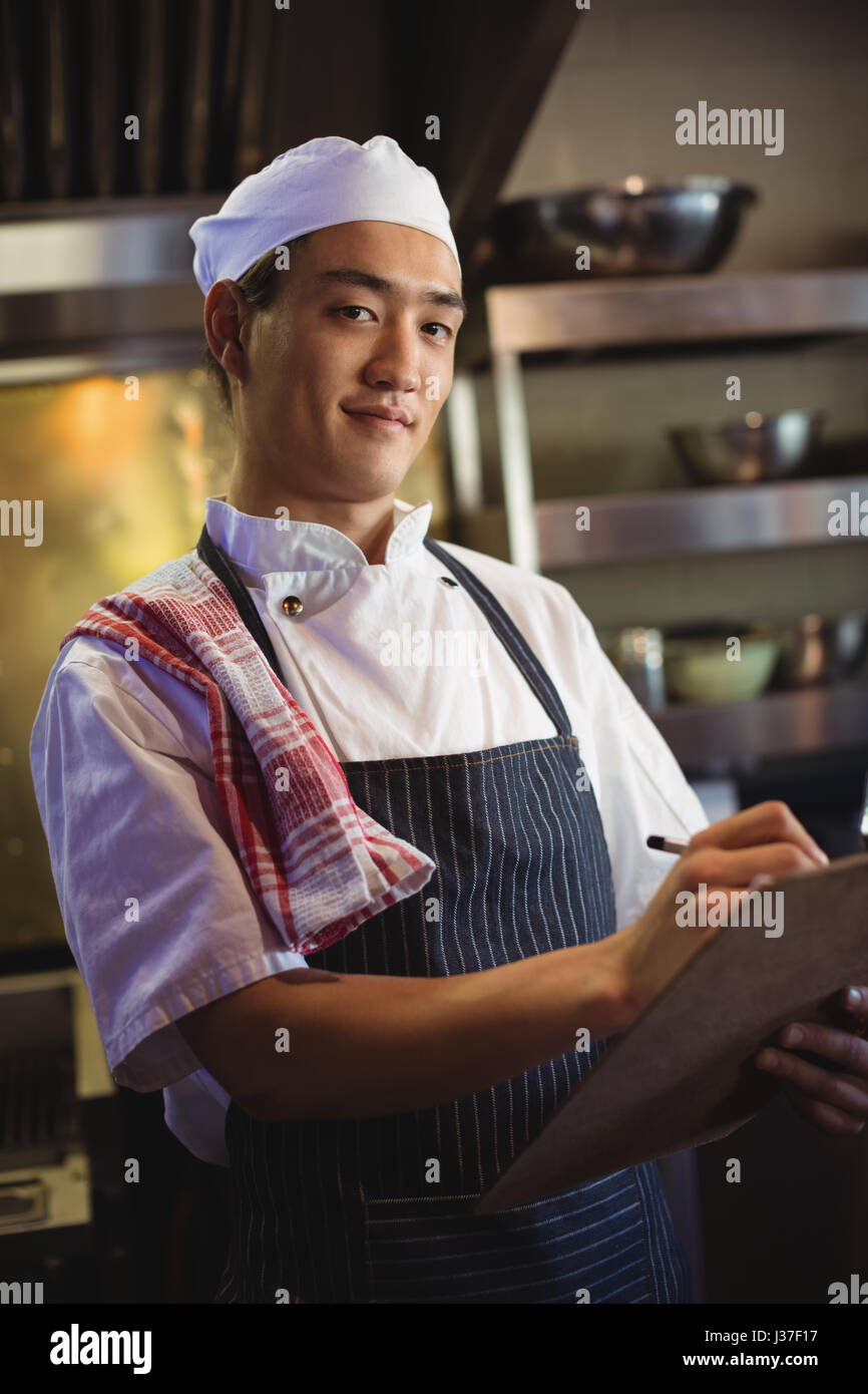 Portrait of chef writing on a clipboard in the commercial kitchen Stock ...