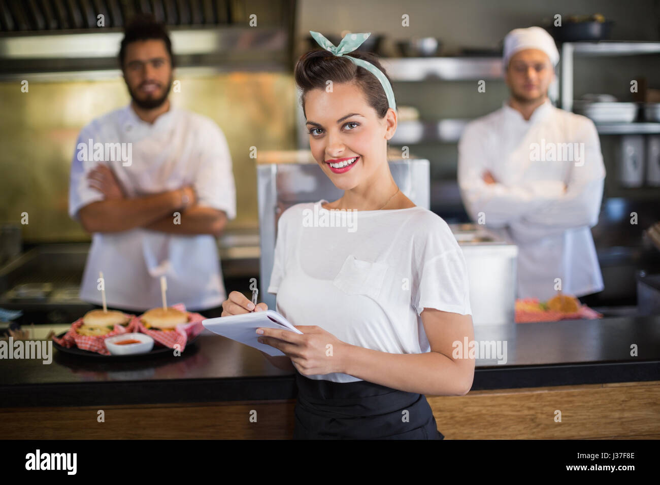 Portrait of waitress writing while chef standing in kitchen Stock Photo ...