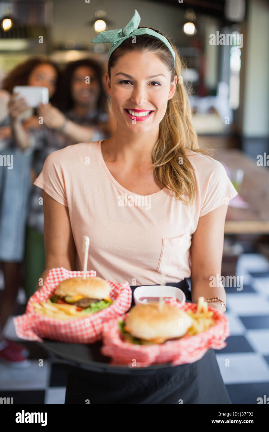 Portrait of happy waitress serving burgers in restaurant Stock Photo ...