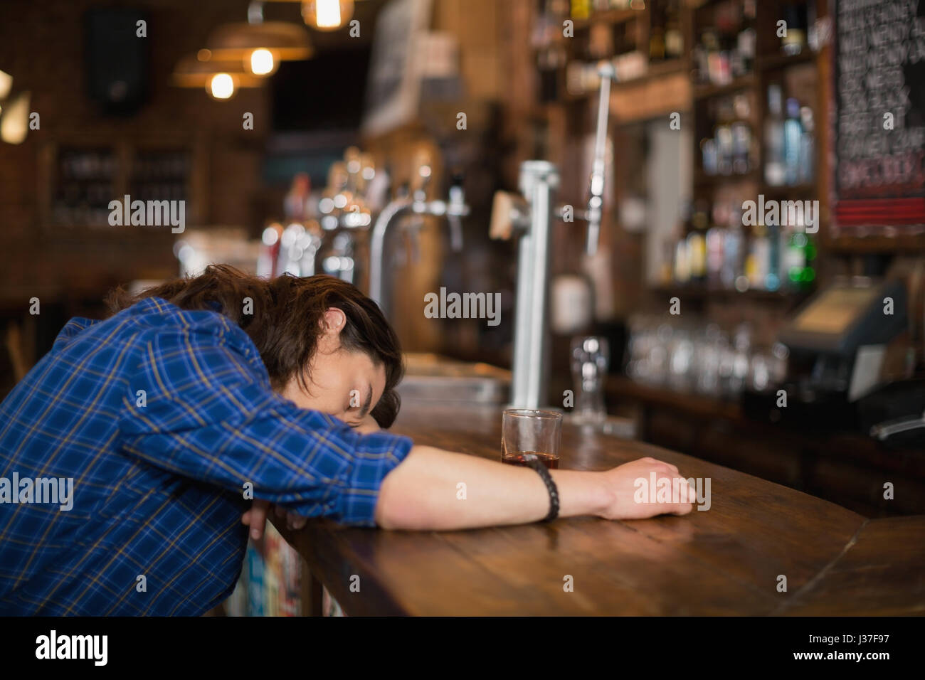 Depressed man leaning on counter in pub Stock Photo - Alamy