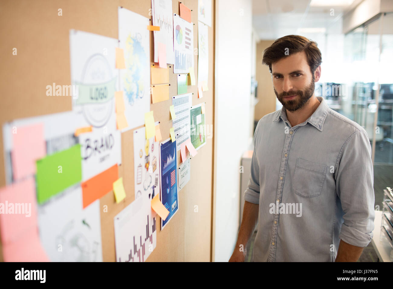 Portrait of businessman standing by soft board at office Stock Photo ...