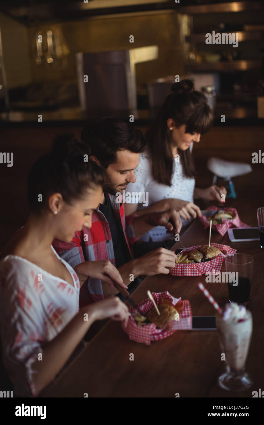 Friends having burger together at restaurant Stock Photo - Alamy
